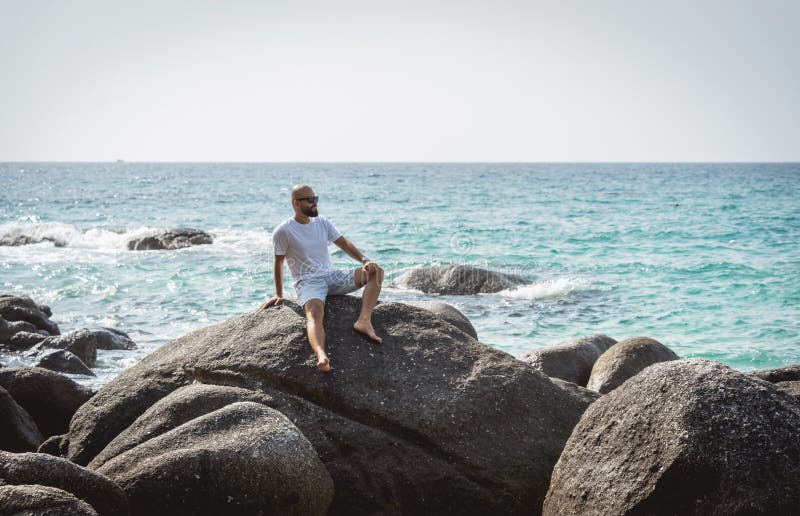 Young Man Relaxing on the Beach while Sitting on an Stones Stock Photo ...