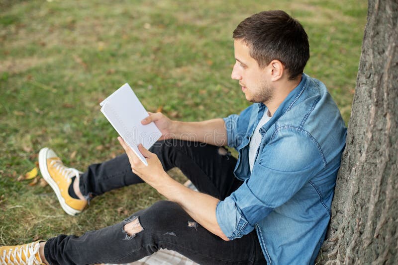 Young Man Relaxing And Reading Book While Sit On Lawn Happy Man