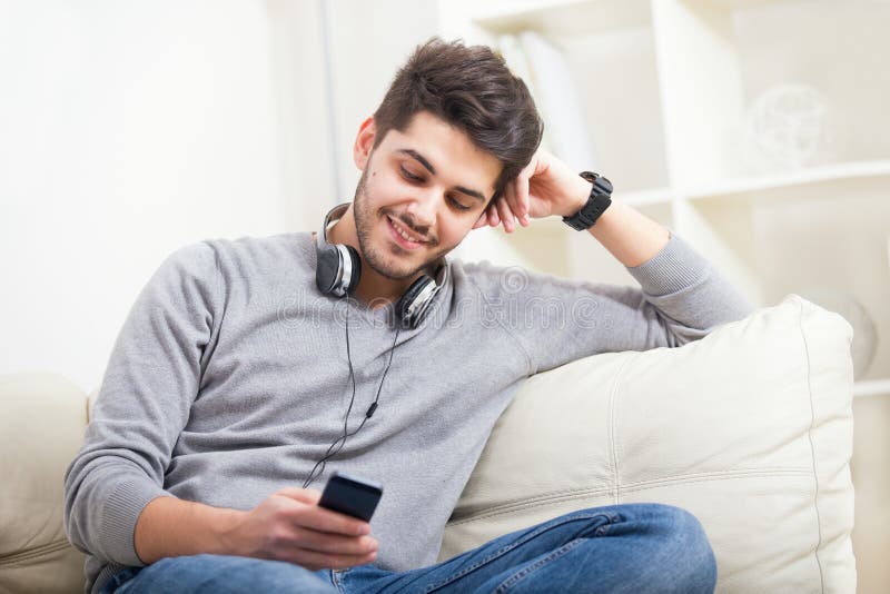 Young Man Relaxing on Sofa and Looking at His Smart Phone Stock Photo ...