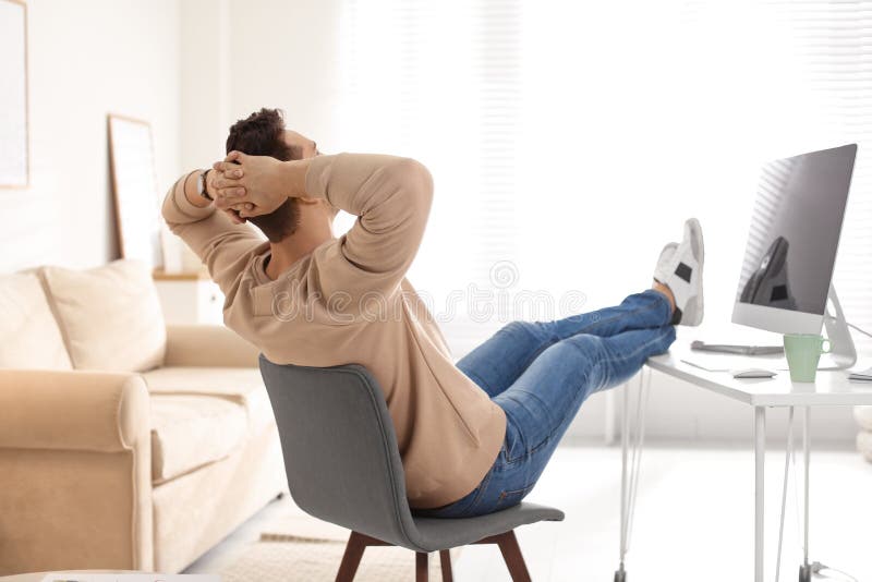 Young Man Relaxing at Table in Office Stock Photo - Image of monitor ...