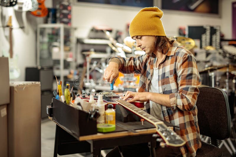Young Man Repairing an Acoustic Guitar with a Screwdriver Stock Photo ...