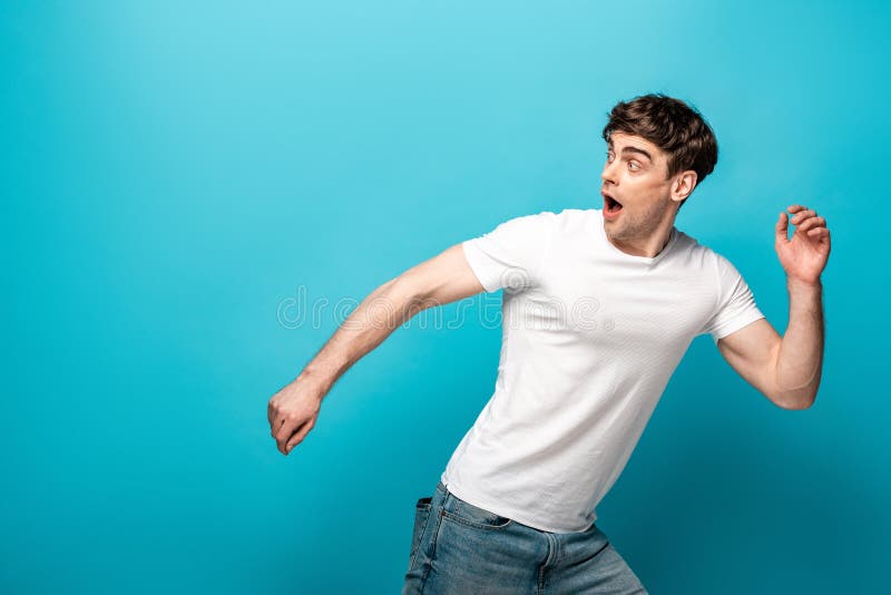 Young Man Running Away and Looking Back on Blue Background Stock Photo ... Young Man Running Away and Looking Back on Blue Background Stock Photo ...