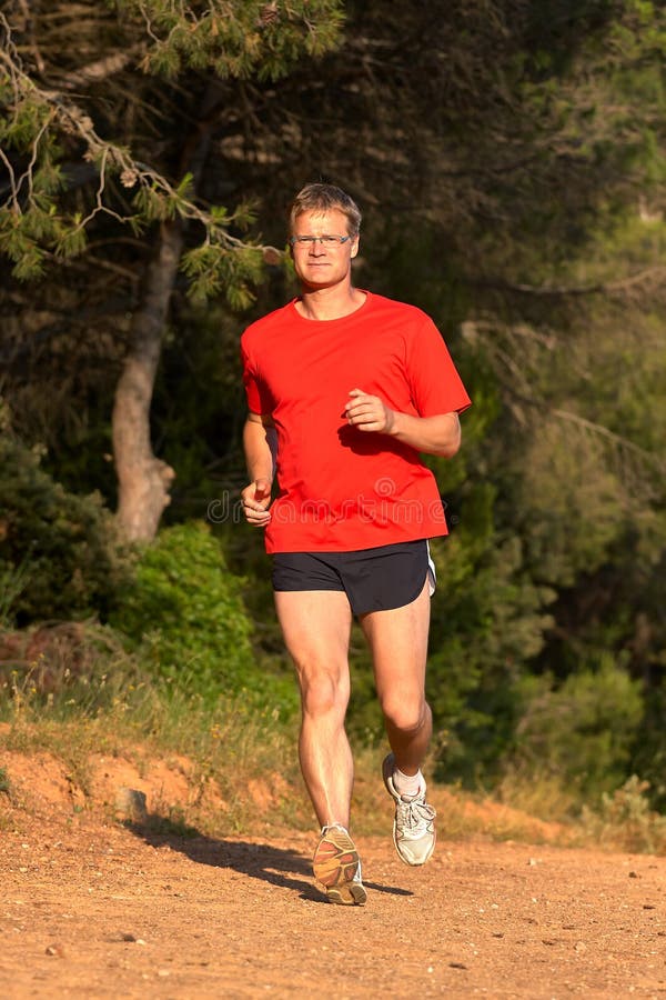 Young Man Running on the Forest Road at Springtime Stock Photo - Image ...