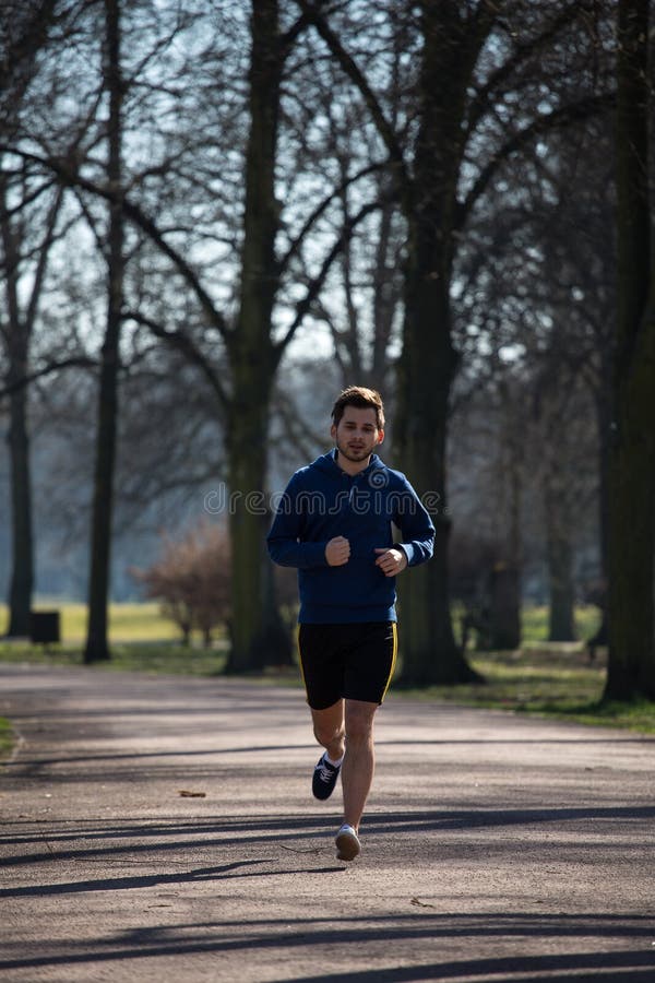 Young Man Runs through the Park Stock Photo - Image of listening ...
