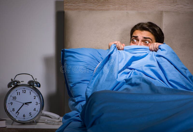 Young man scared in bed stock image. Image of bedtime - 230390153