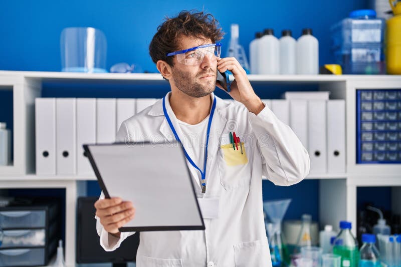 Young Man Scientist Talking on Smartphone Holding Clipboard at ...