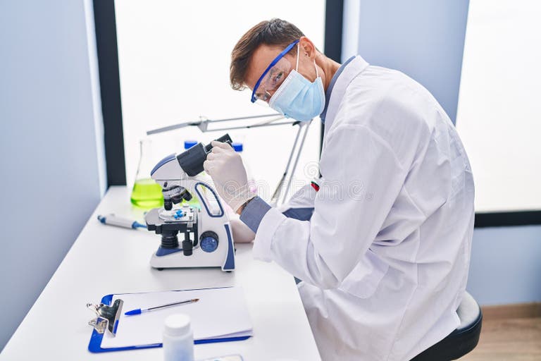 Young Man Scientist Wearing Medical Mask Using Microscope at Laboratory ...