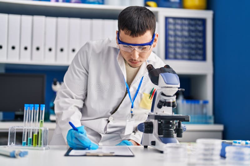 Young Man Scientist Writing on Document Using Mircoscope at Laboratory ...