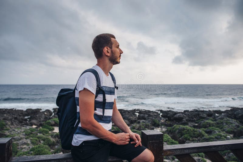 Young Man Sits on a Railing by the Sea Stock Photo - Image of looking ...