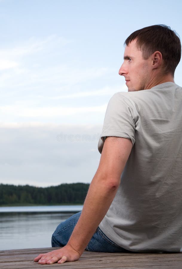 A Young Man Sitting Alone by the Water Stock Photo - Image of blue ...