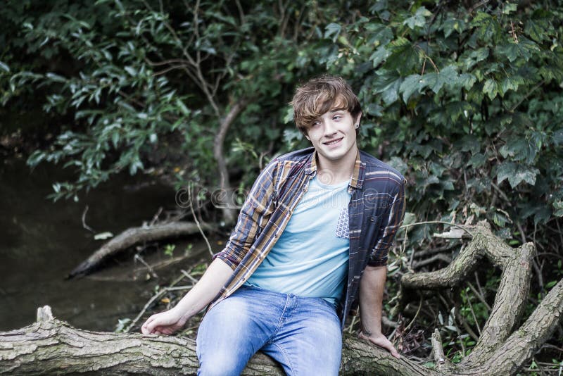 Young Man Sitting on Branch Over a Stream Stock Photo - Image of nature ...
