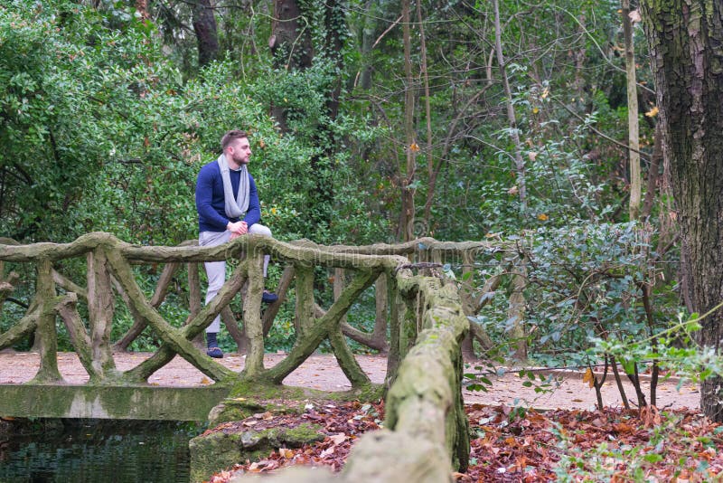 Young Man Sitting on Bridge with Stone Railing Stock Image - Image of ...