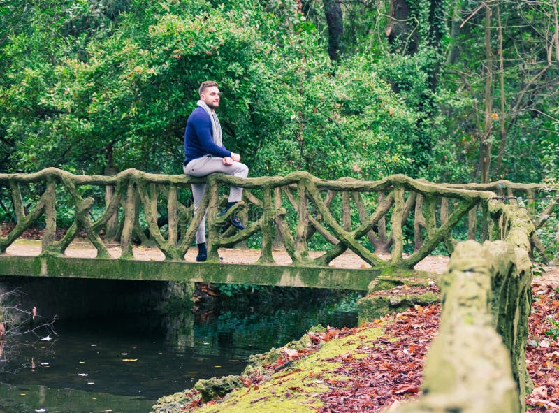 Young Man Sitting on Bridge with Stone Railing Stock Image - Image of ...