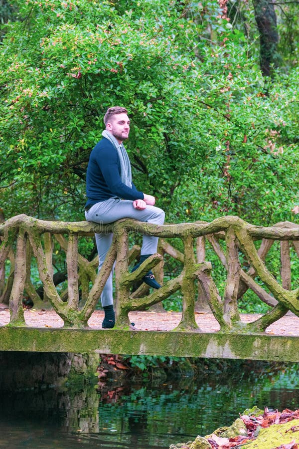 Young Man Sitting on Bridge with Stone Railing Stock Image - Image of ...