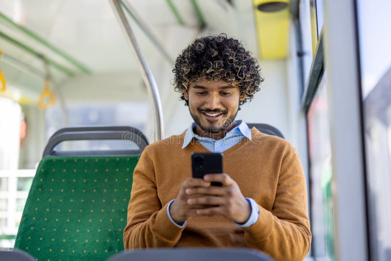 Young Man on Public Transport Smiling while Using Smartphone, Wearing ...