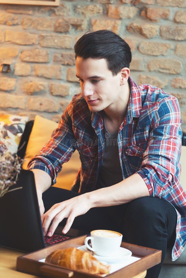 Young Man Sitting at a Cafe, Using a Laptop Stock Image - Image of ...
