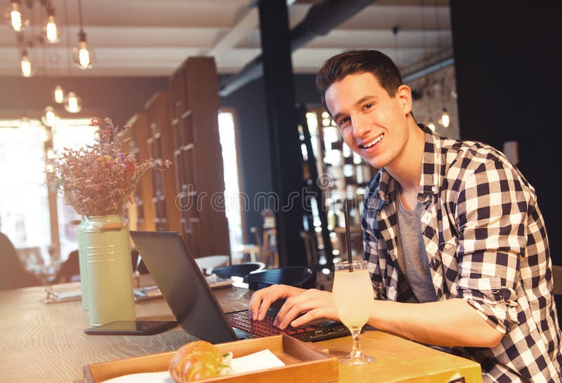 Young Man Sitting at a Cafe, Using a Laptop Stock Image - Image of ...
