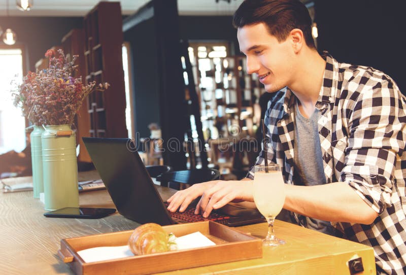 Young Man Sitting at a Cafe, Using a Laptop Stock Photo - Image of ...