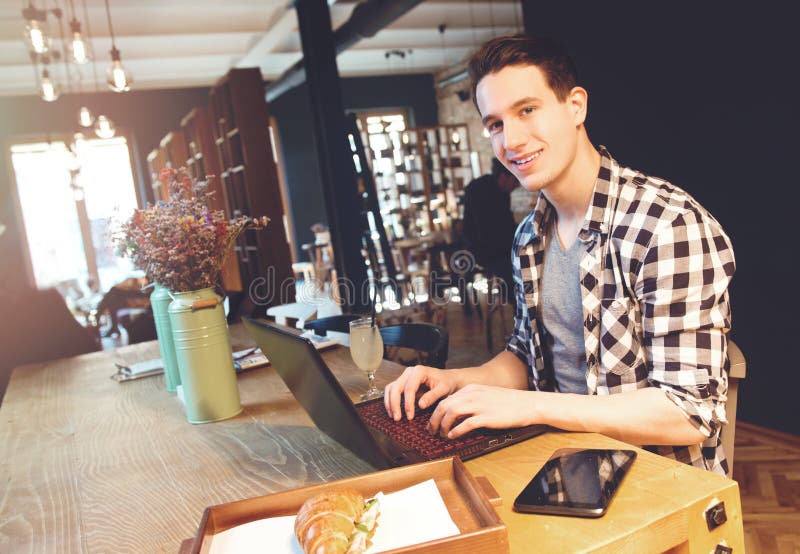Young Man Sitting at a Cafe, Using a Laptop Stock Image - Image of ...
