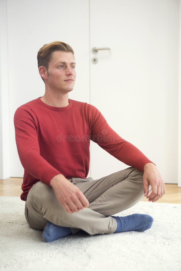 Young Man Sitting on Carpet and Looking Thoughtfully Stock Photo ...