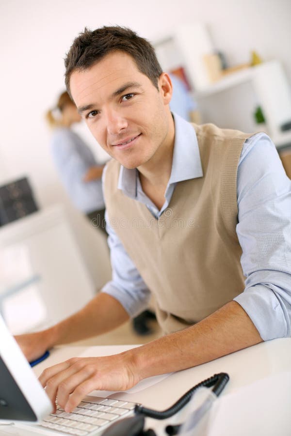 Young Man Sitting at Desk in Office Stock Photo - Image of assistant ...