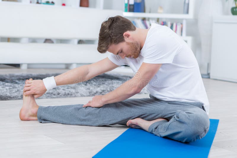 Young Man Sitting on Exercise Mat and Stretching Stock Image - Image of ...