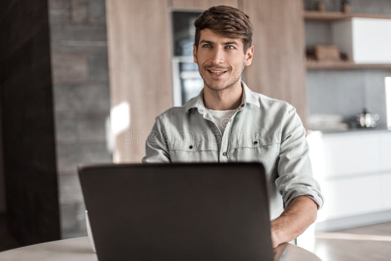 Young Man Sitting in Front of Open Laptop in Kitchen Stock Photo ...