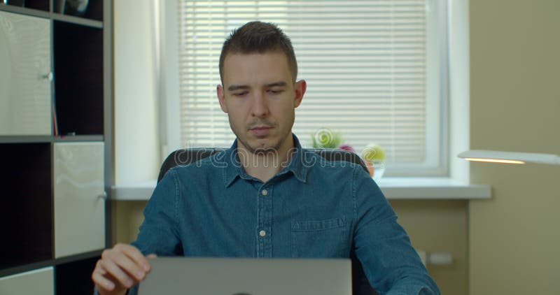 Young Man Sitting at His Desk at Home, Opens and Starts Using Laptop ...