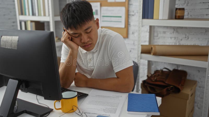 Young Man Sitting in a Home Office Resting His Head on His Hand in ...