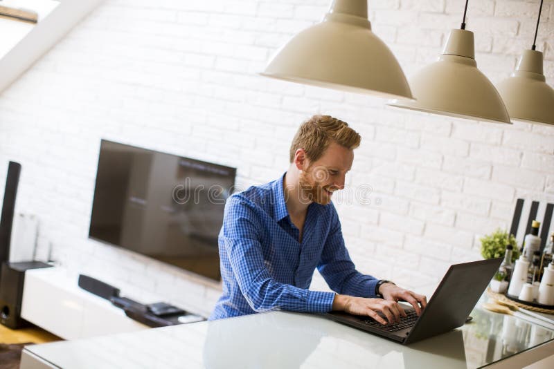Young Man Sitting on Kitchen Desk at Home and Using Laptop Stock Image ...