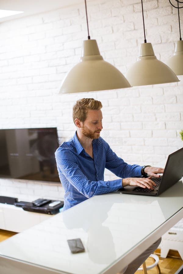 Young Man Sitting on Kitchen Desk at Home and Using Laptop Stock Photo ...