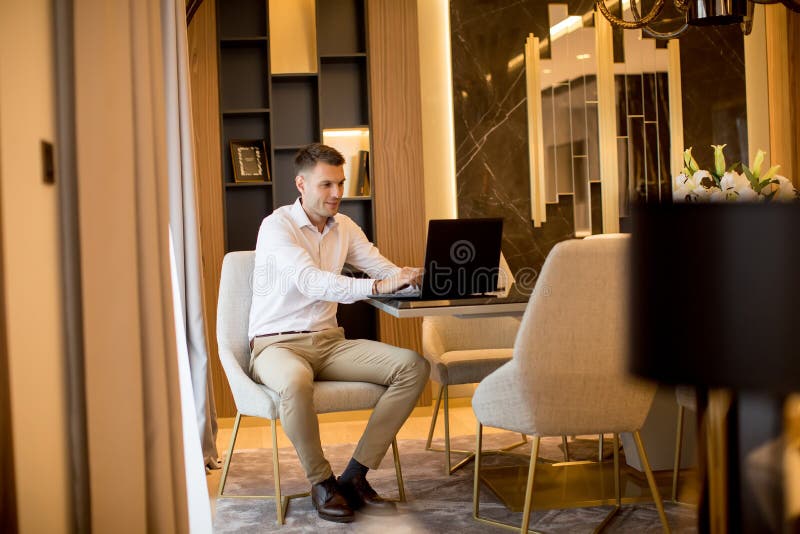 Young Man Sitting in a Luxurious Room in Front of a Laptop Computer ...