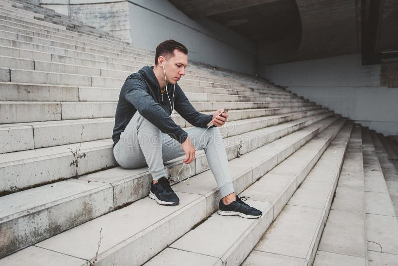 Young Man Sitting on the Modern Bridge in the City, Using His ...