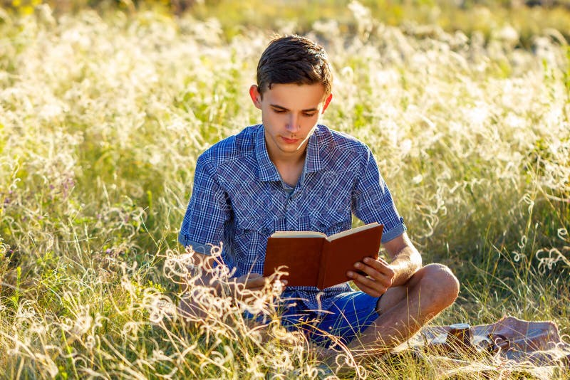 Young Man Sitting in Nature Reading a Book Stock Photo - Image of ...