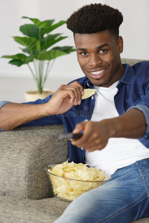 Young Man Sitting on Sofa Watching Tv and Eating Chips Stock Photo ...