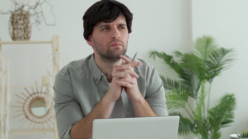 Young Man Sitting at the Table in Front of Computer and Thinking of ...