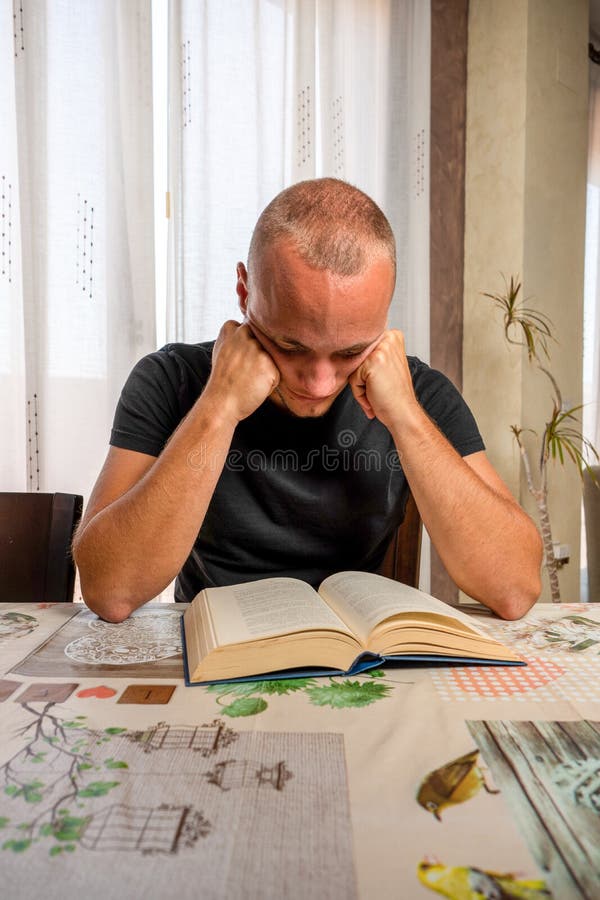 Young Man is Sitting on Table and Reading a Book Stock Photo - Image of ...