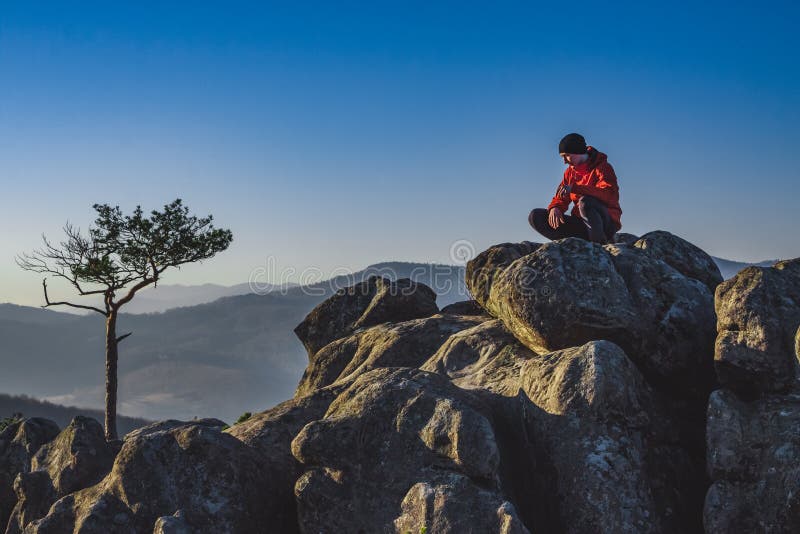 Young Man Sitting on the Top of the Rock in Sunrise Stock Photo - Image ...
