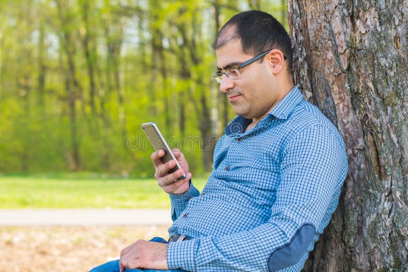 Young Man Sitting Under a Tree Stock Photo - Image of casual, outside ...