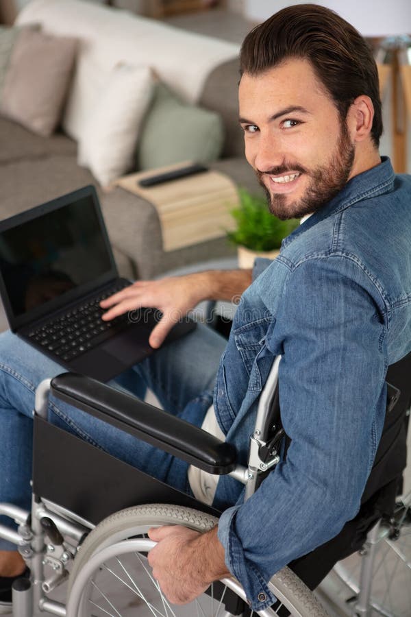Young Man Sitting in Wheelchair Using Laptop at Home Stock Image ...