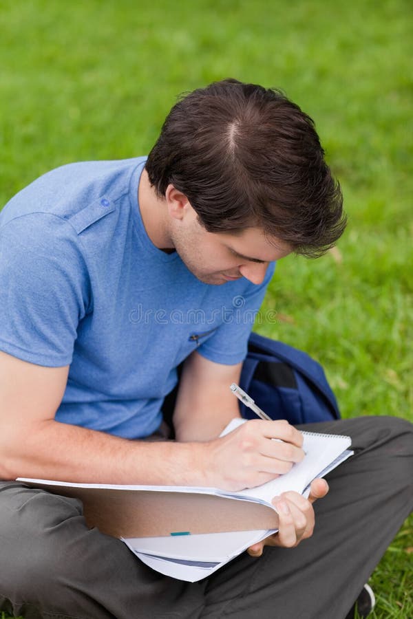 Young Man Sitting while Writing on His Notebook Stock Photo - Image of ...