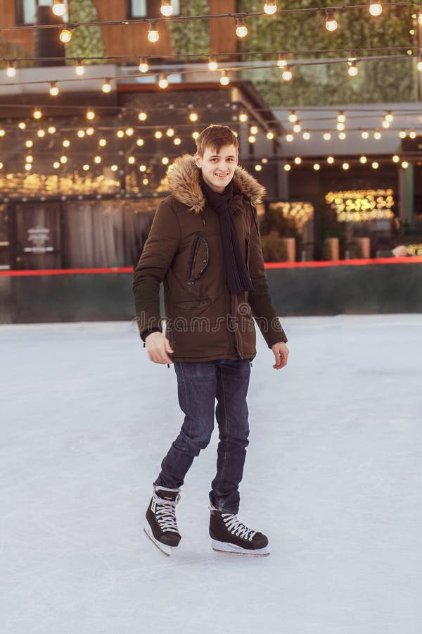 A Young Man Skating on a Skating Rink, Looks at the Camera and Smiles ...