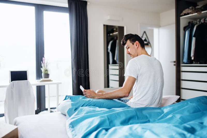 Young Man with Smartphone in Bed at Home, Text Messaging. Stock Image ...