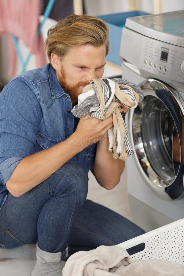 Young Man Smelling Clothes while Doing Laundry Stock Photo - Image of ...