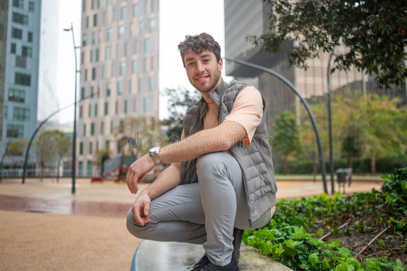 Young Man Smiling and Crouching in a City Park Stock Image - Image of ...