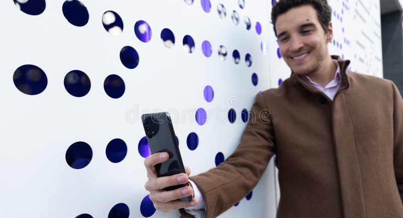Young Man Smiling at the Phone Camera on a Wall with Hole Patterns ...