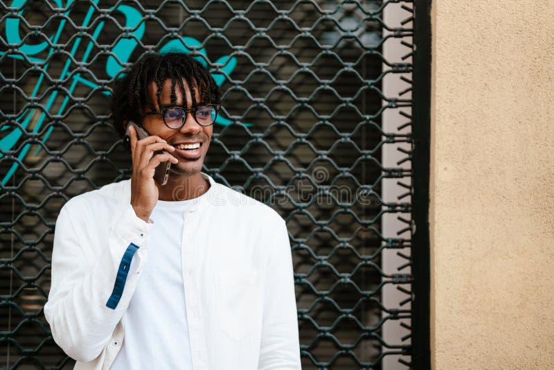 Young Man Smiling and Using Cellphone Standing Over Chain Link Fence ...