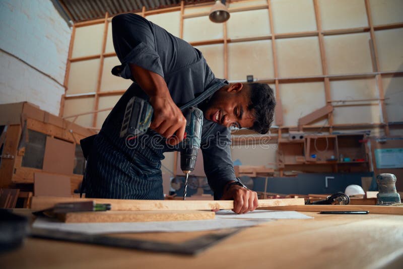 Young Man Smiling while Using Drill on Wood during Work at Woodworking ...