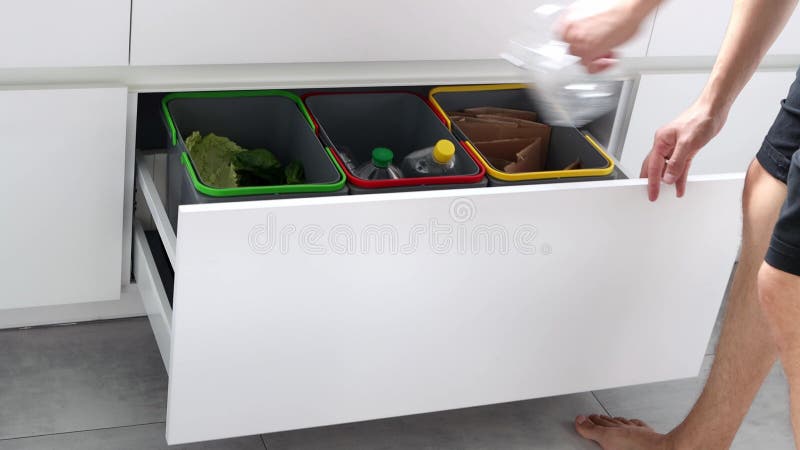 A Young Man Sorts Garbage in Containers in the Kitchen. Modern Kitchen ...