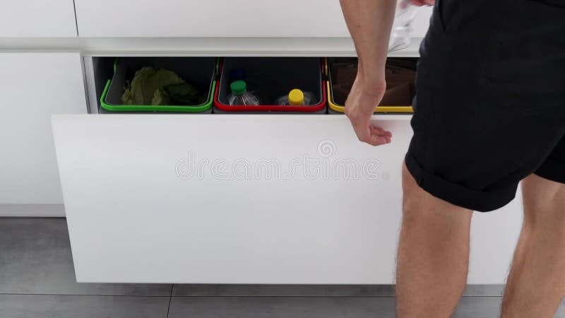 A Young Man Sorts Garbage in Containers in the Kitchen. Modern Kitchen ...